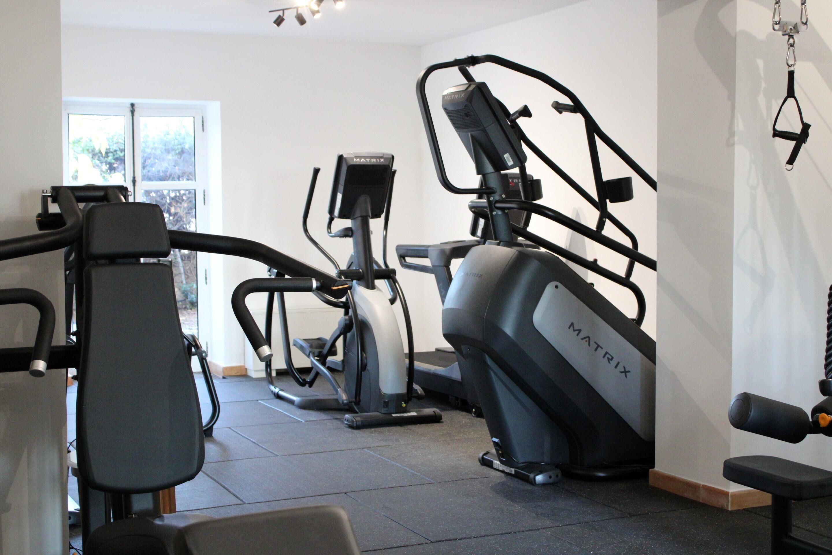 Academia com diversos equipamentos de exercício, incluindo esteiras e elípticos.