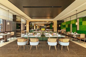 Um restaurante moderno com área de jantar central, cabines e uma parede verde com textura.