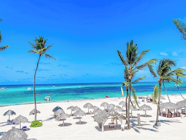 Na praia, areia branca, guarda-sóis, massagens na praia