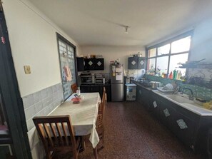 Uma cozinha compacta com mesa e cadeiras, geladeira, micro-ondas e pia.