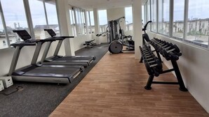 Uma academia com esteiras, bicicleta ergométrica e aparelhos de musculação.