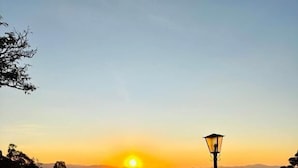 Piscina com vista para o pôr do sol, cercada por degraus de pedra e um poste de luz.