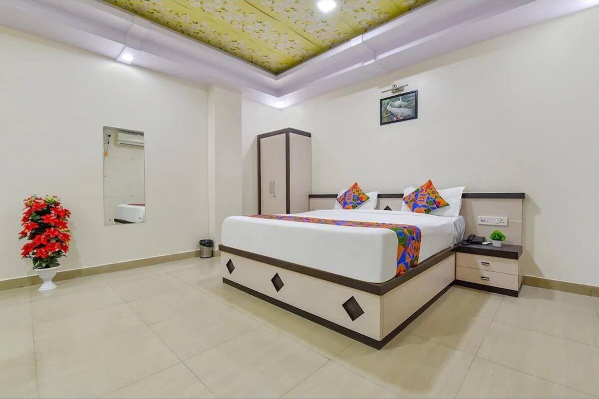 Quarto com cama, mesas de cabeceira, guarda-roupa, espelho e planta em vaso.