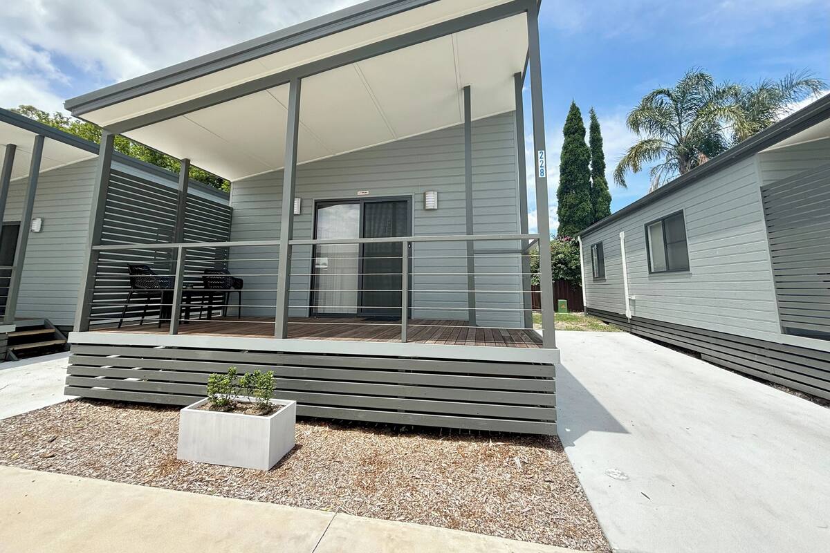 Uma casa moderna térrea com varanda coberta, um pequeno jardim e porta de garagem visível.