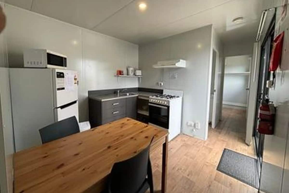 Cozinha compacta com uma mesa de jantar de madeira, fogão a gás e micro-ondas.