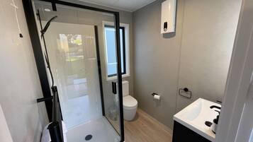Uma casa de banho moderna com cabine de chuveiro em vidro, sanita e lavatório.