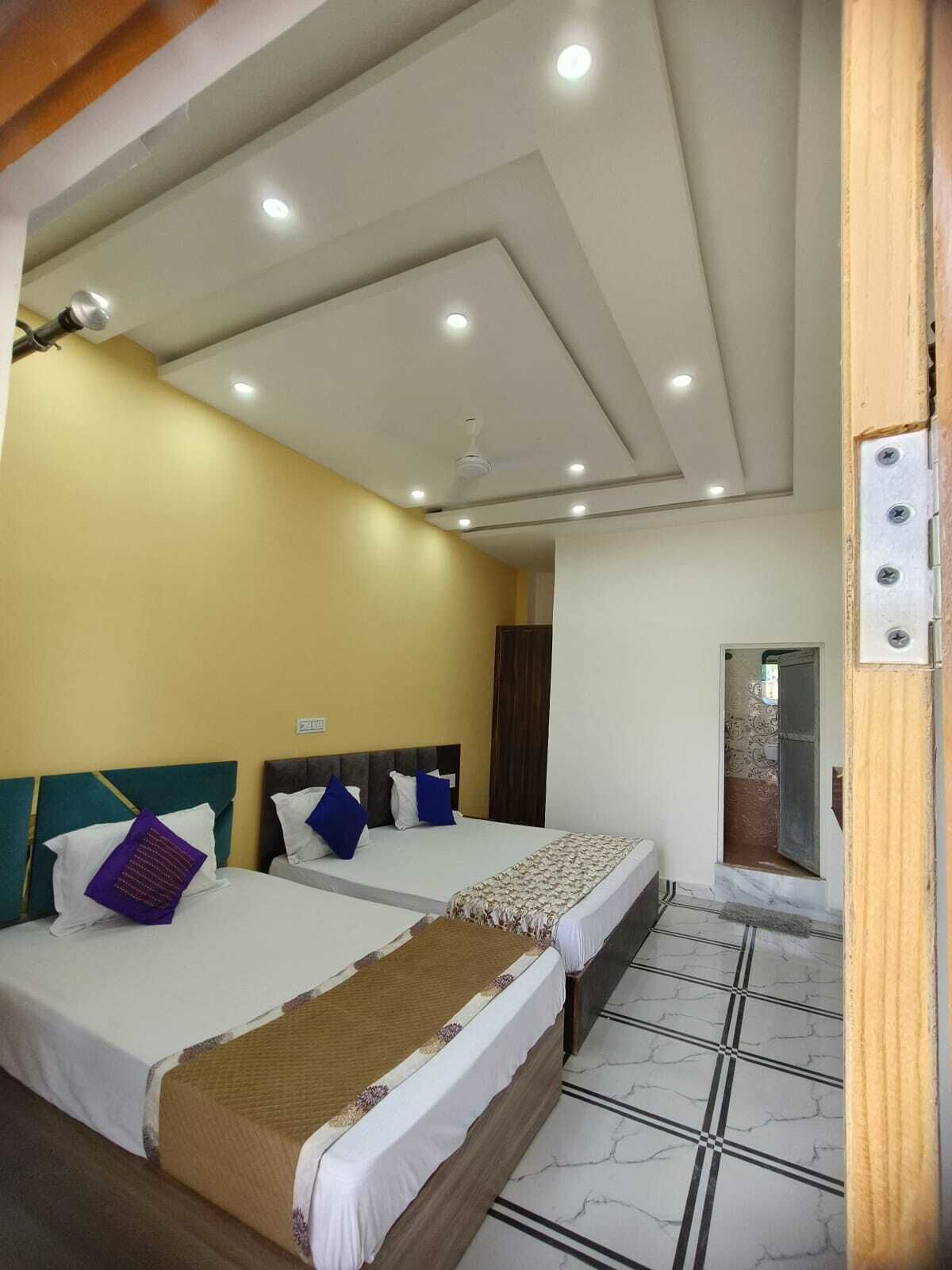 Quarto de hotel com duas camas, ventoinha no teto, iluminação embutida e piso revestido com azulejos.