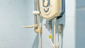Chuveiro fixado na parede, com painel de controle, chuveiro manual e tubulações.