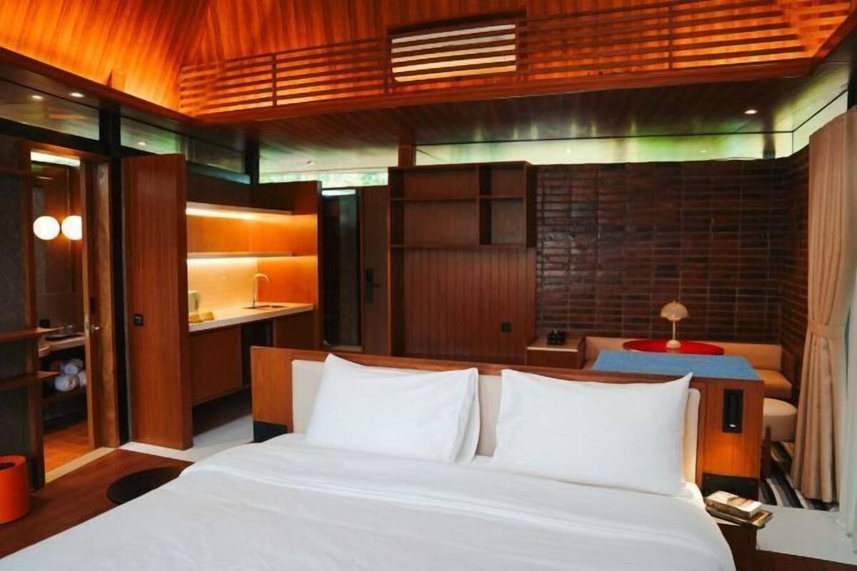 Quarto de hotel com cama, mesas de cabeceira, escrivaninha e área de estar.