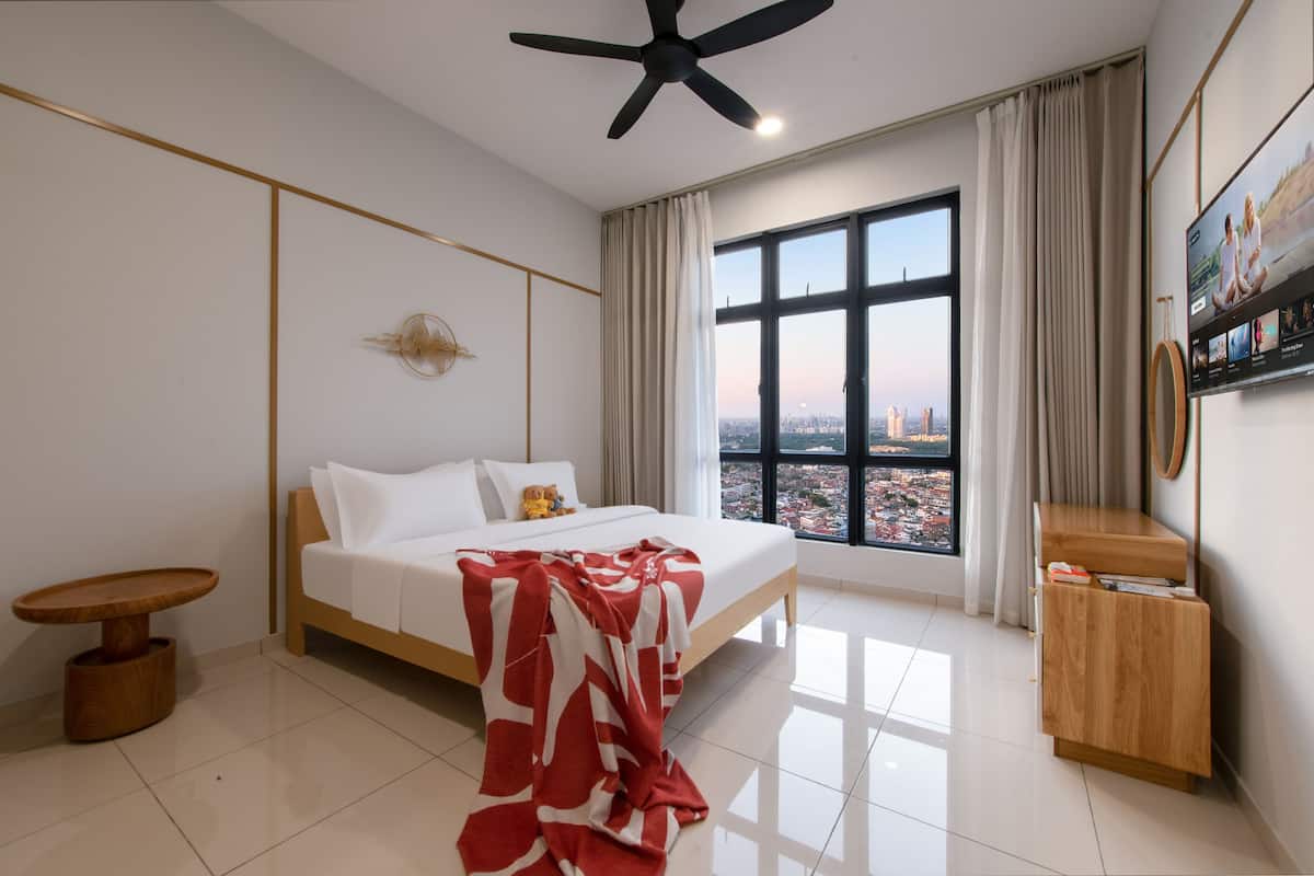 Quarto de hotel moderno com uma cama grande, vista para a cidade, ventoinha no teto e mesa de cabeceira de madeira.
