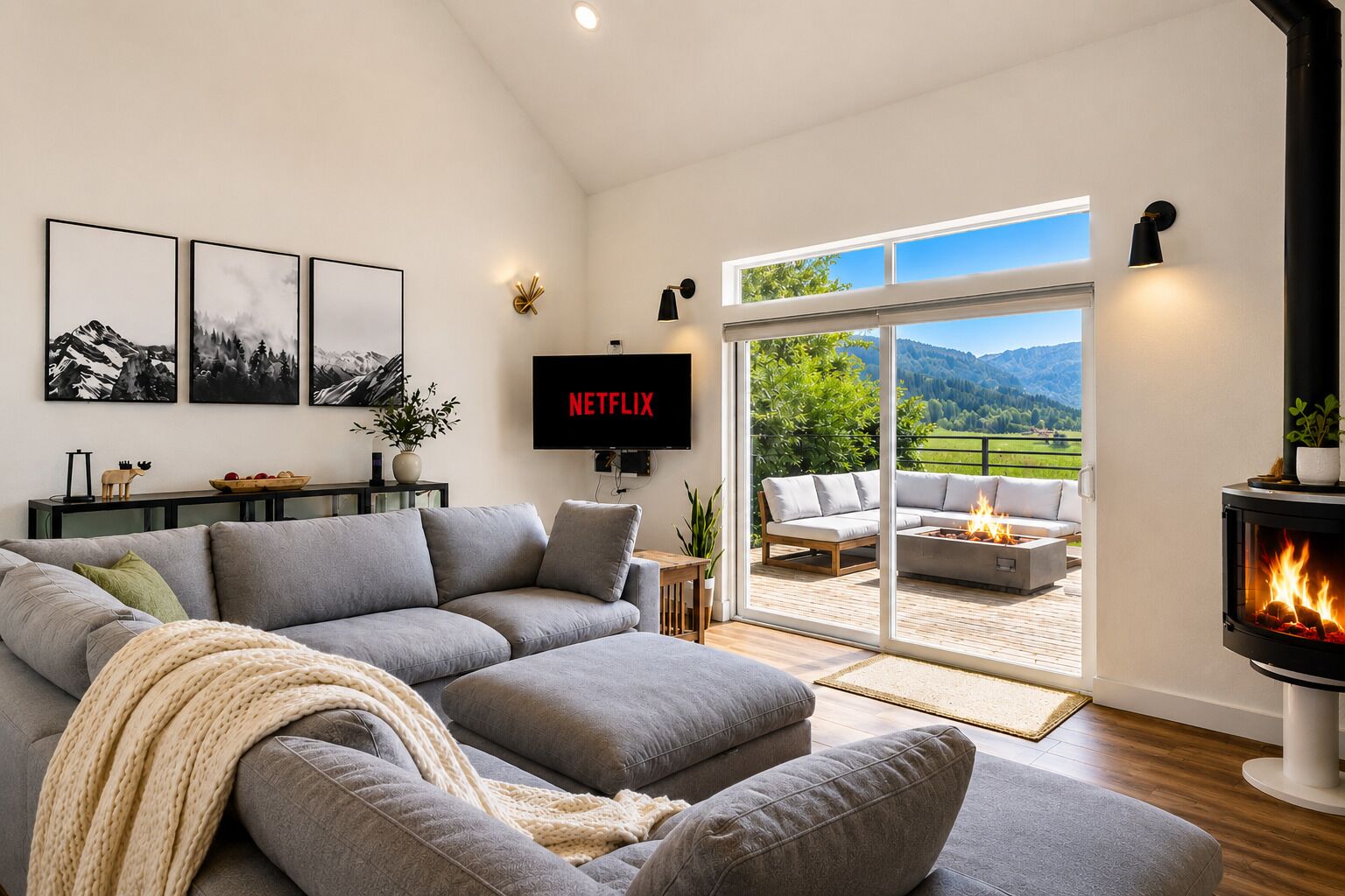 Uma sala de estar moderna com um sofá modular cinzento, uma televisão de tela plana, uma lareira e uma porta de vidro deslizante que dá para um deck externo.