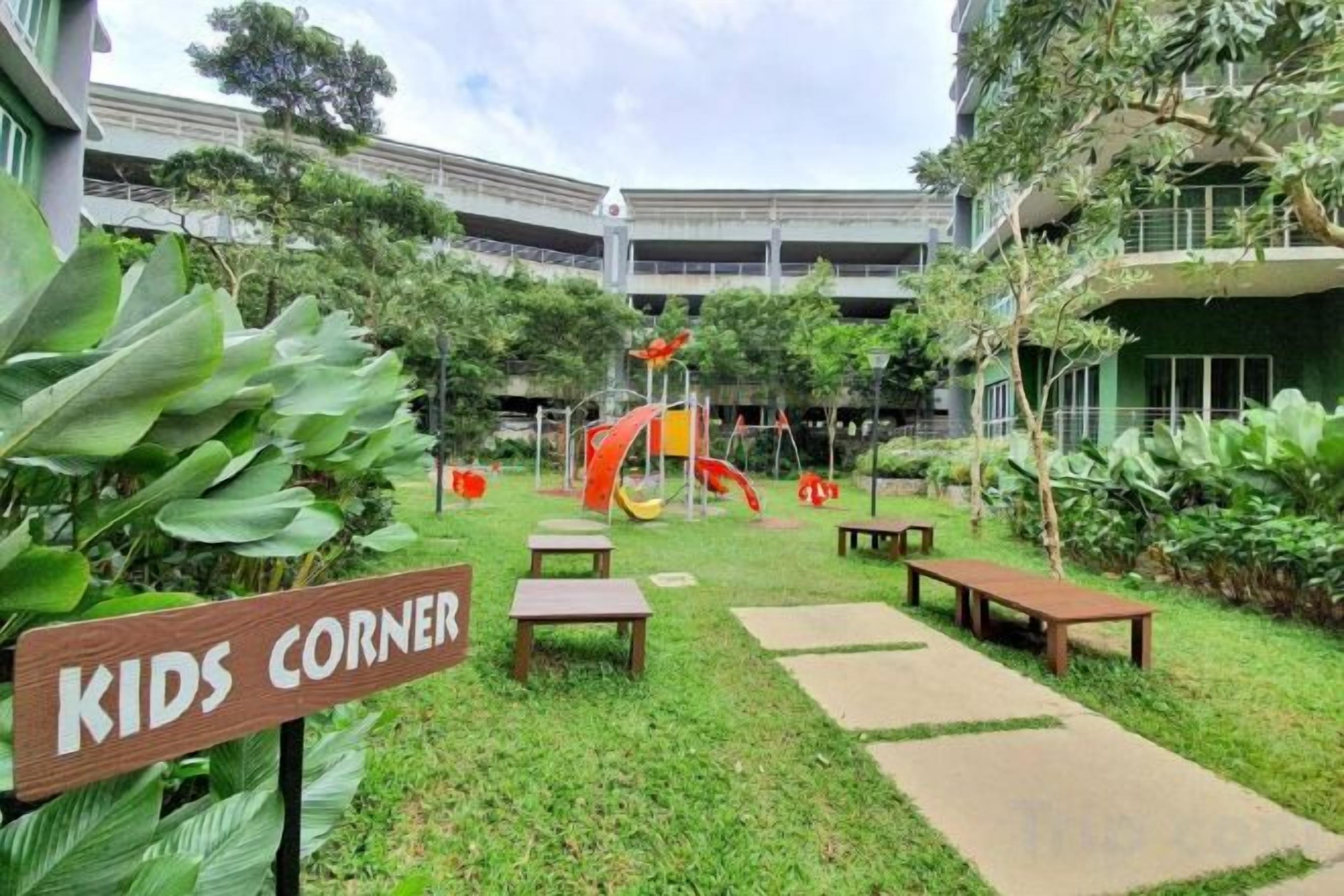 Pátio com área de recreação, bancos e placa com a inscrição 'KIDS CORNER'.