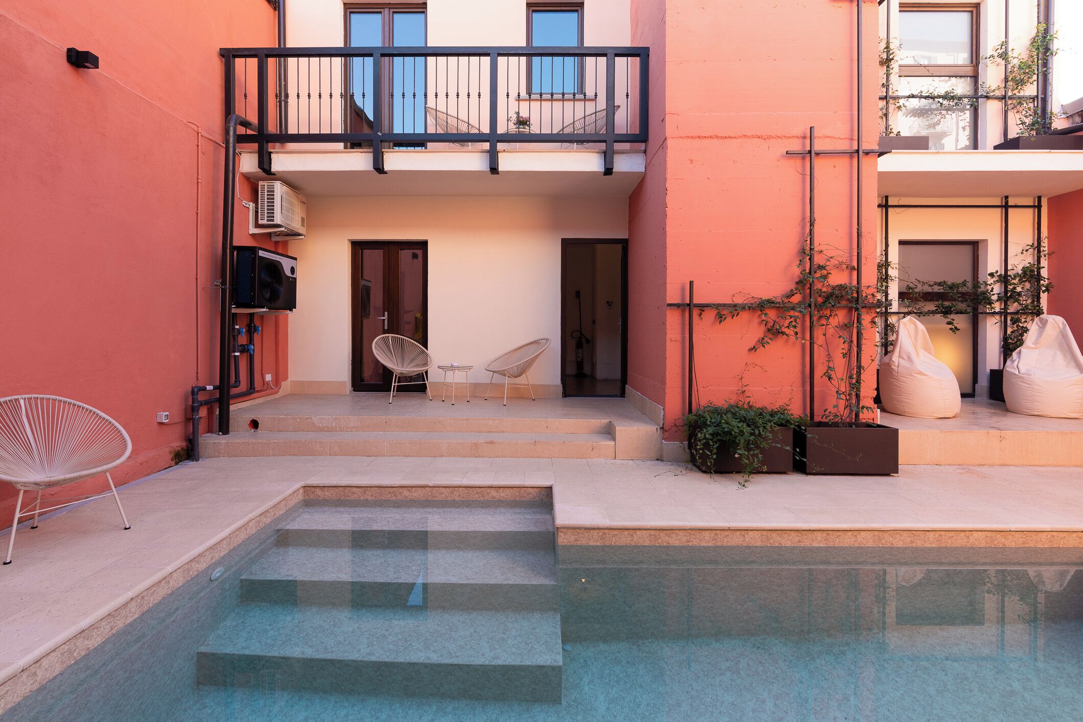 Um edifício residencial com uma pequena piscina ao ar livre, uma varanda com guarda-corpo e uma porta de acesso ao interior.
