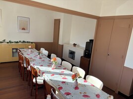 Uma sala de jantar com uma mesa comprida, cadeiras e um armário com eletrodomésticos.