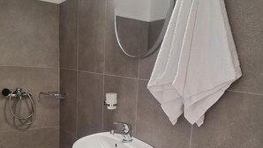 Uma casa de banho moderna com uma pia branca, um espelho redondo e um porta-toalhas.