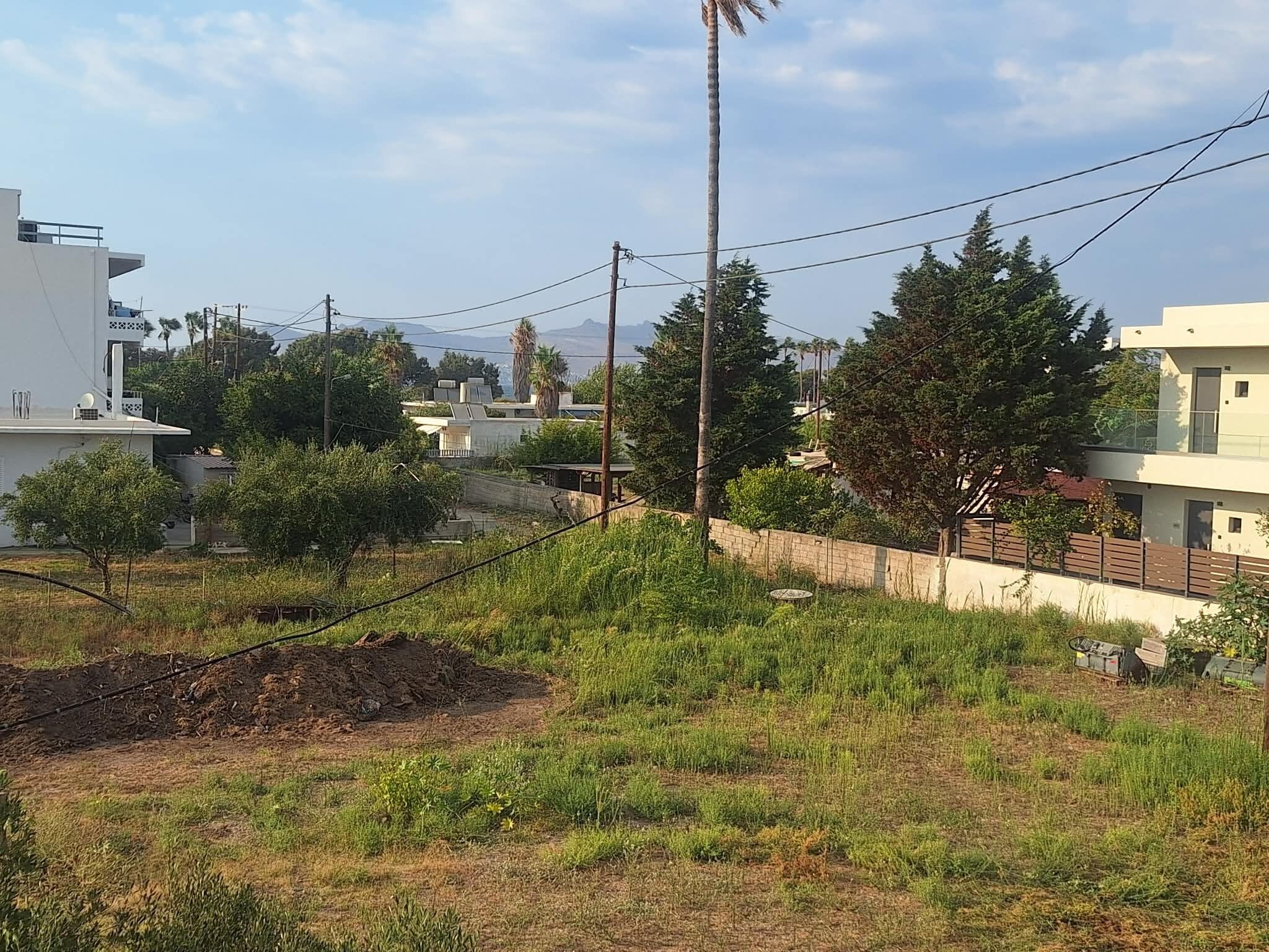 Zona residencial com edifícios modernos, céu claro e vegetação variada.