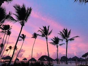 Na praia, areia branca, espreguiçadeiras, guarda-sóis