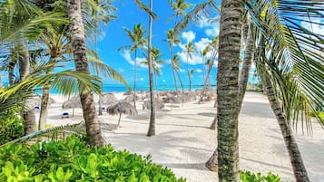 Na praia, areia branca, espreguiçadeiras, guarda-sóis