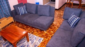 Sala de estar com sofá cinza, mesa de centro de madeira e tapete estampado.