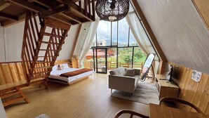 Quarto aconchegante com escada de madeira, cama, sofá e escrivaninha com cadeira.