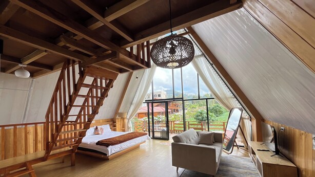 Quarto com escada de madeira, cama, sofá e secretária com computador.