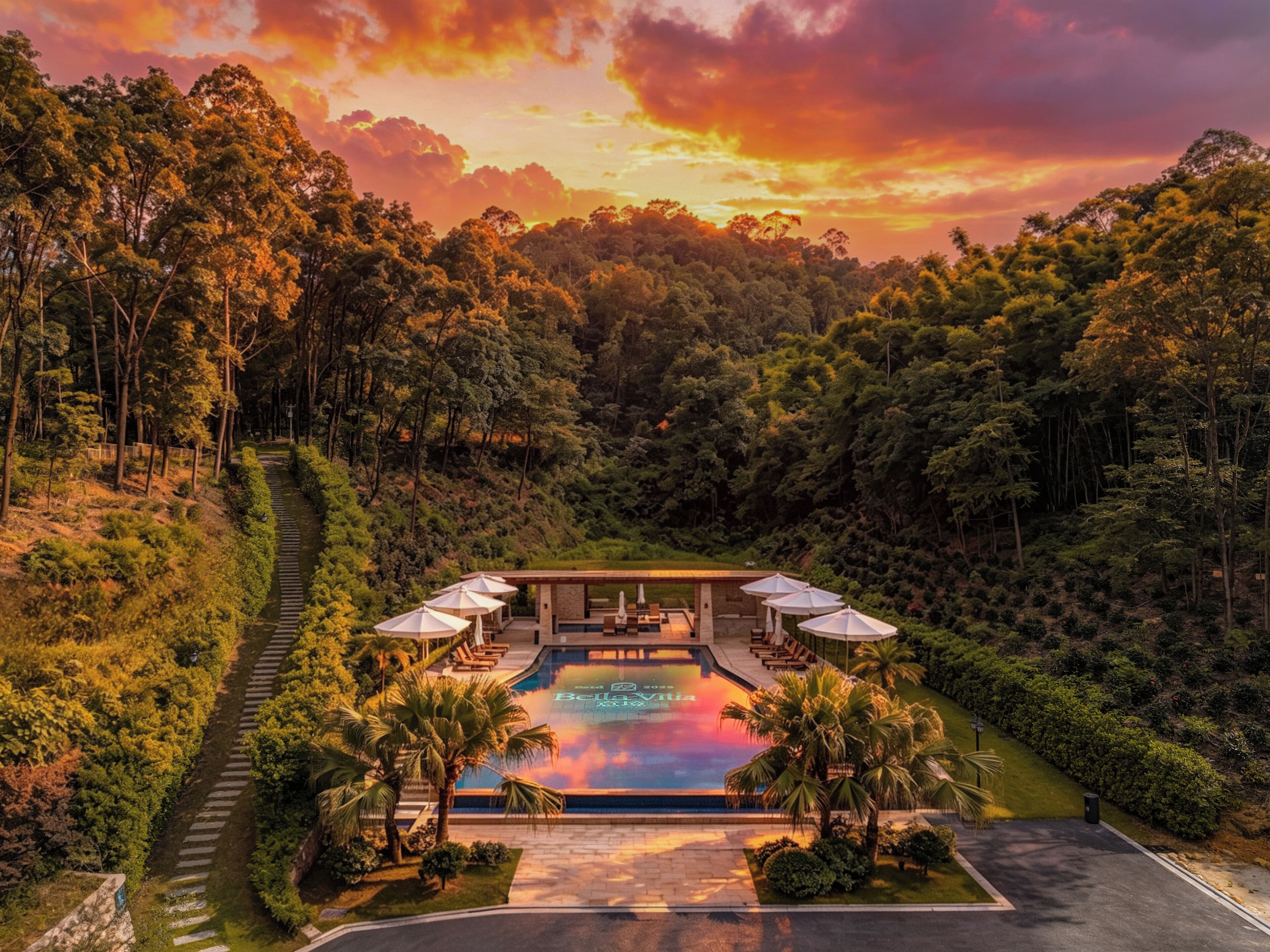 Um resort com piscina, área de estar externa e uma exuberante paisagem florestal ao fundo.