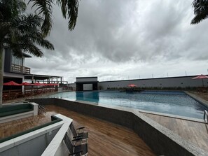 Piscina com deck de madeira, espreguiçadeiras e guarda-sóis.