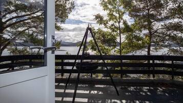 Um banco com um tripé e uma panela, com vista para um lago, árvores e montanhas ao fundo.