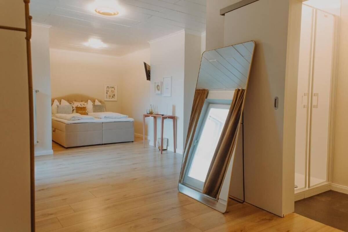 Quarto de hotel com uma cama, mesa de cabeceira e espelho apoiado na parede.