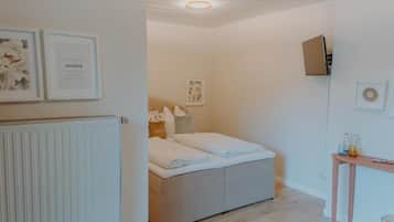 Quarto com cama, mesa de cabeceira e radiador.