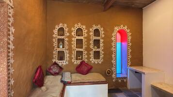 Um quarto com piso xadrez, um banco com almofadas e uma parede com arcos decorativos.
