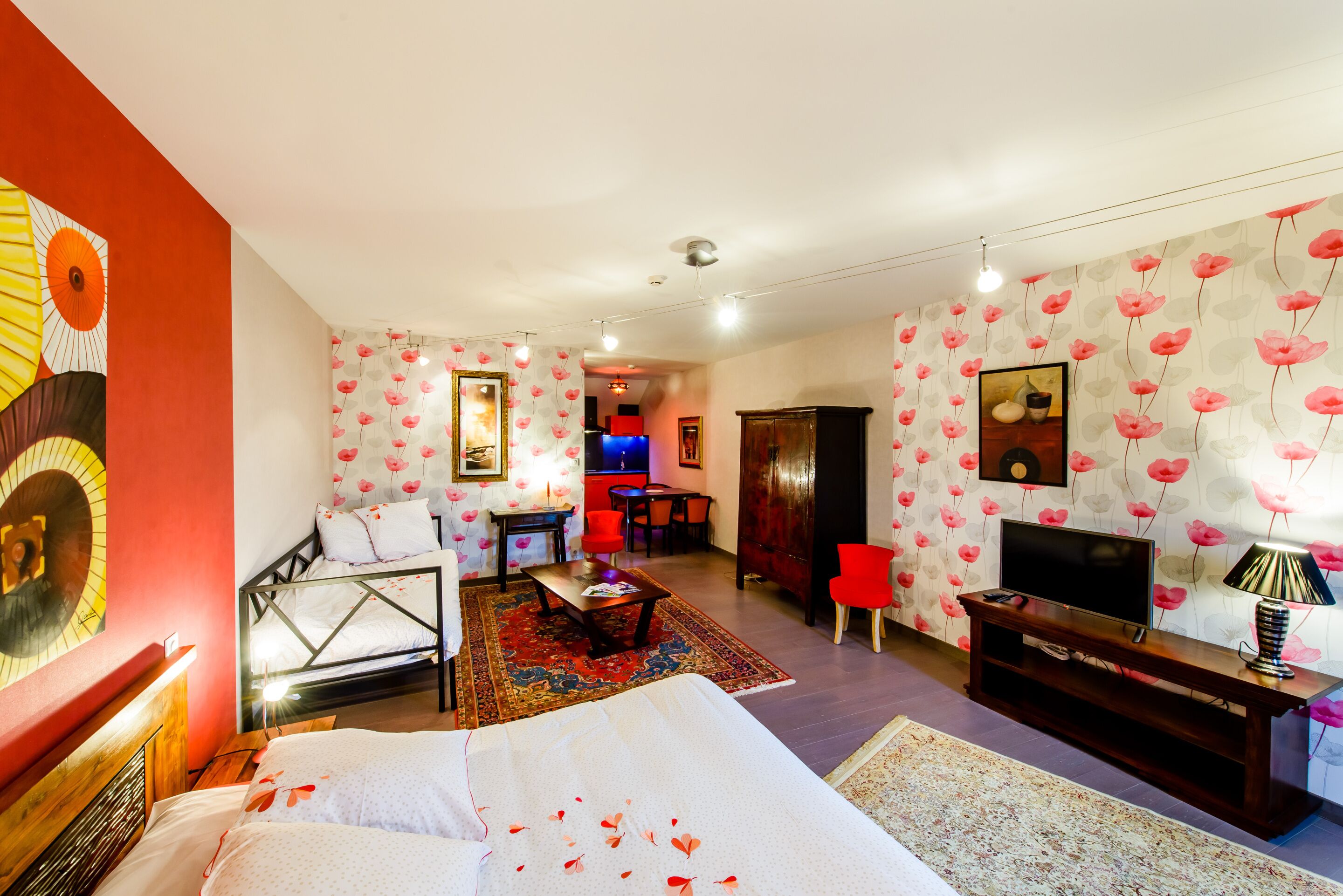 Quarto de hotel com cama, televisão, escrivaninha e área de refeições.