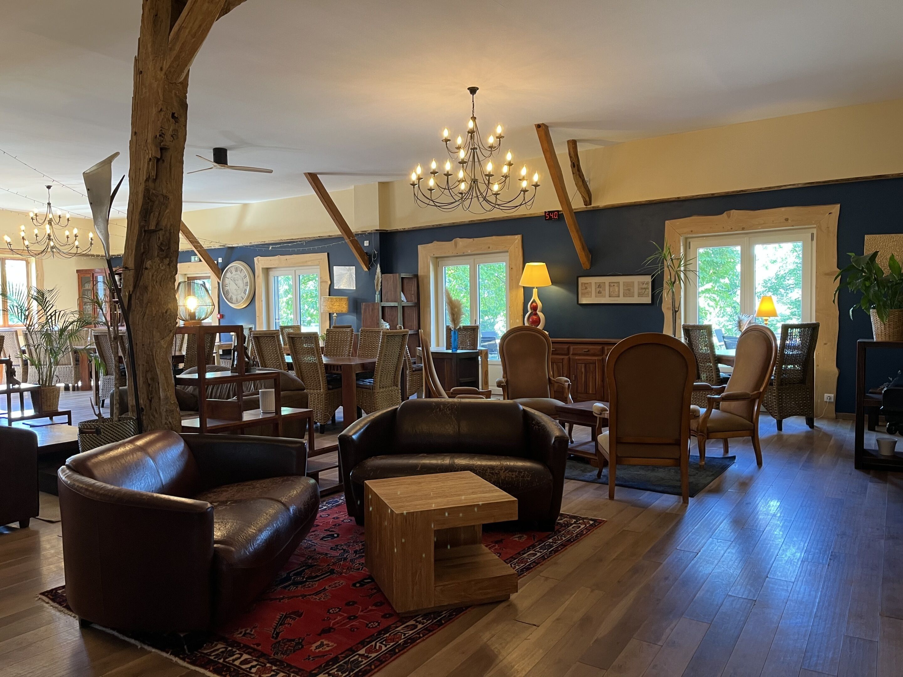 Uma sala de estar ampla, com um grande tronco de árvore de madeira, sofás de couro e um candelabro.