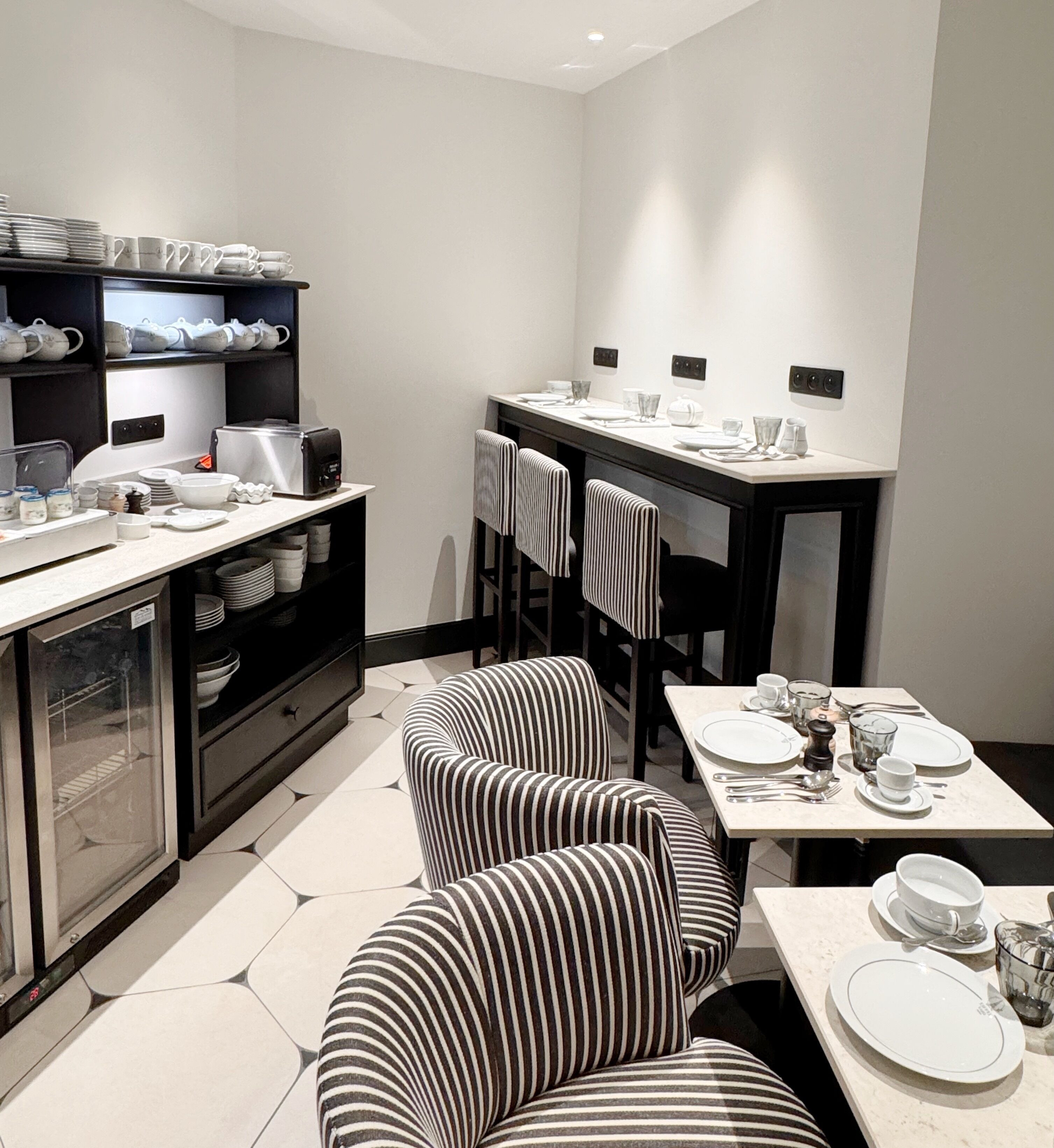 Uma cozinha moderna com sofás listrados, uma mesa de jantar posta para quatro pessoas e uma geladeira.