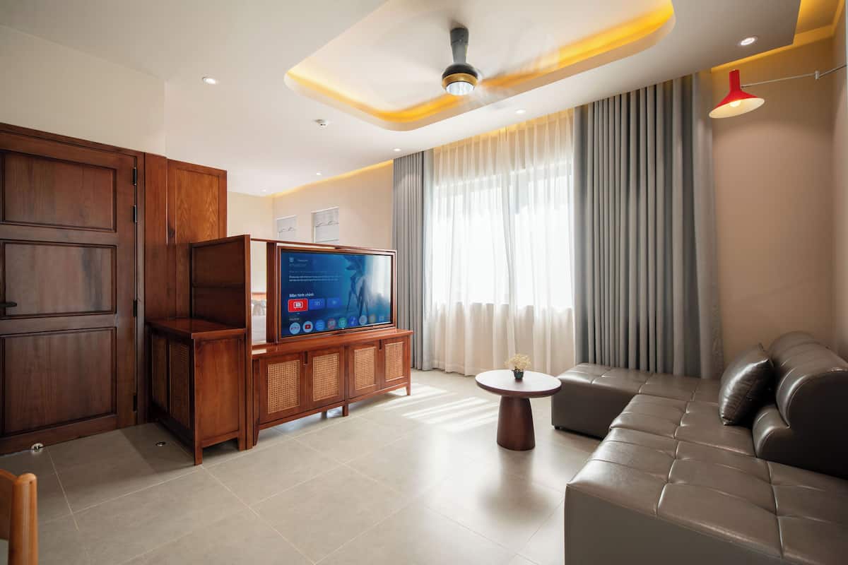 Uma sala de estar moderna com uma televisão de tela plana, um sofá, uma mesa de centro e um ventilador de teto.