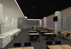 Uma sala de aula moderna com fileiras de mesas e cadeiras, um banco comprido e uma parede com padrões geométricos.