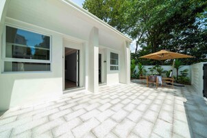 Uma casa moderna com um pátio, incluindo uma mesa e um guarda-sol.