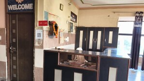 Uma área de recepção com um letreiro 'WELCOME', um balcão com um computador e uma porta com a inscrição '209'.