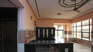 Quarto com uma janela grande, ventilador de teto e bancada com armários.