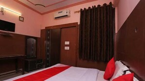 Quarto de hotel com cama, escrivaninha, televisão e guarda-roupa.