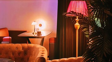 Quarto com um sofá estofado, uma mesa pequena com abajur e um vaso de planta.