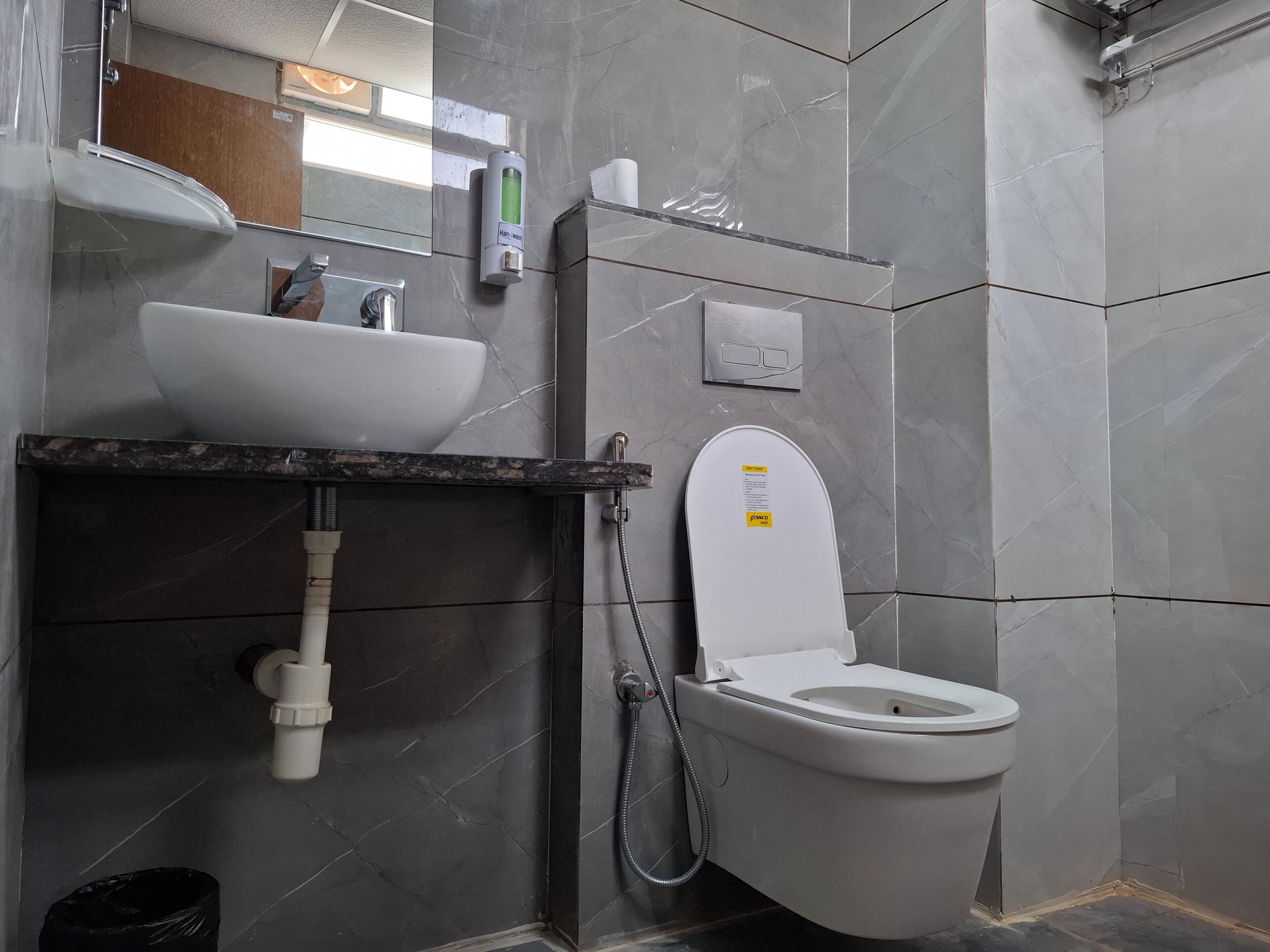 Uma casa de banho moderna com uma pia branca, espelho e sanita.