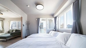 Quarto de hotel moderno com uma cama grande, um sofá e vista para a cidade pela janela.