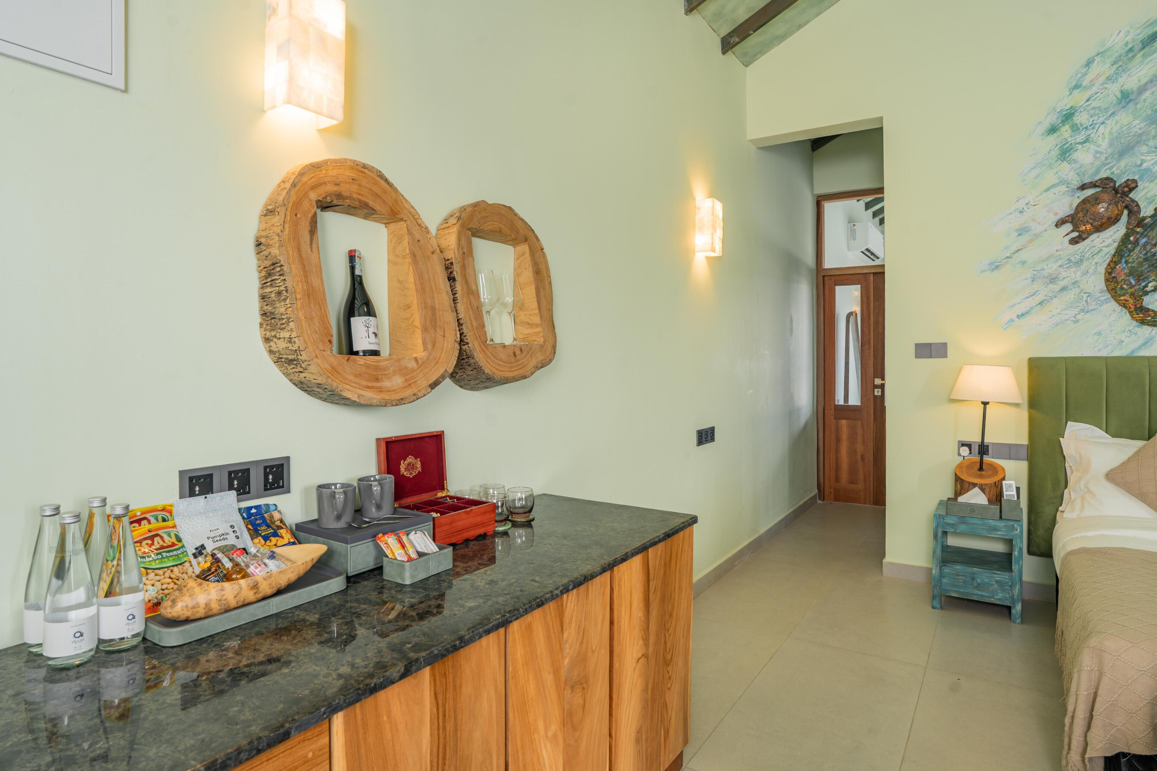 Quarto de hotel com um armário de madeira, uma cama, uma mesa de cabeceira, um espelho fixado na parede e um mural de uma tartaruga marinha.