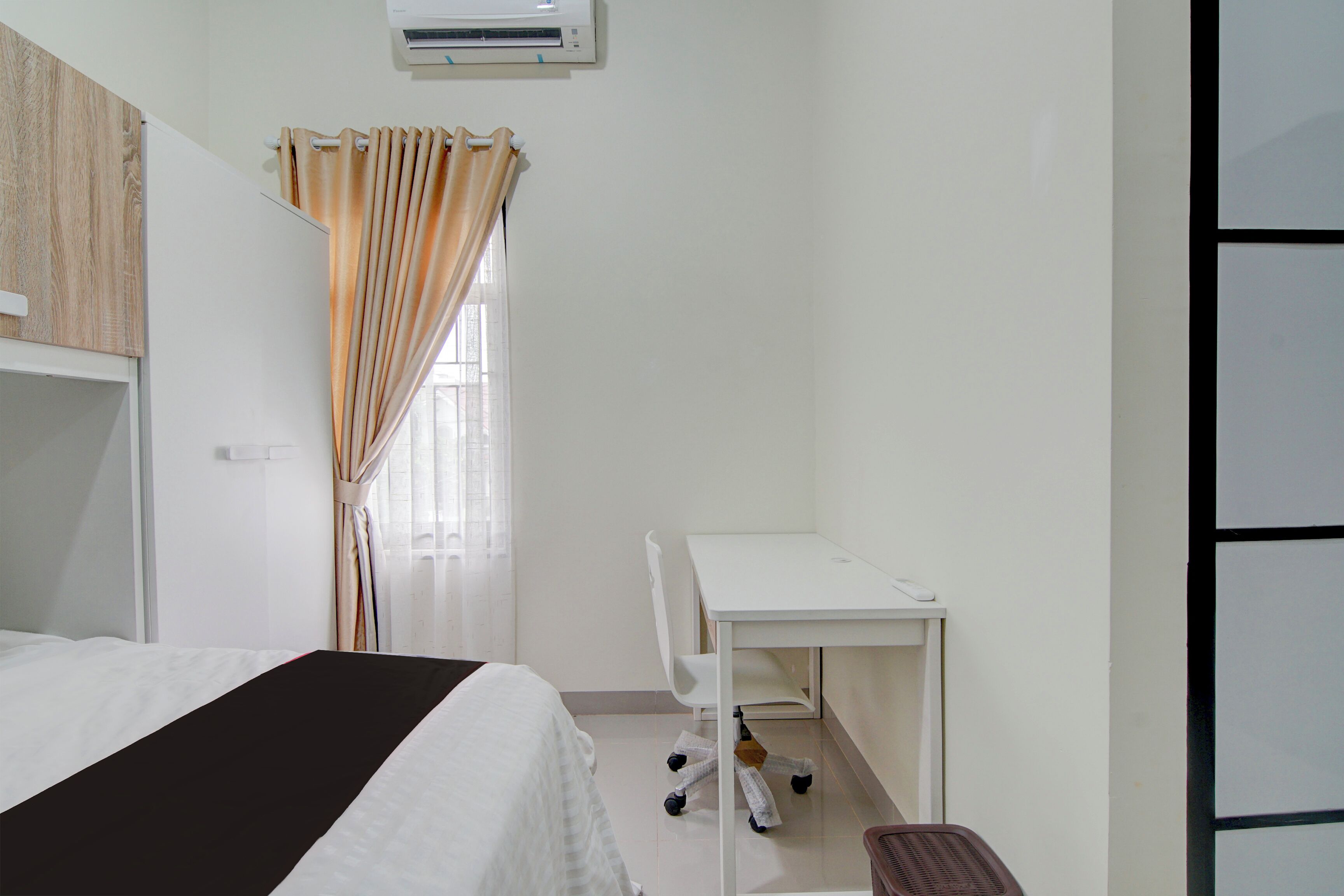 Quarto de hotel com cama, escrivaninha e ar condicionado.