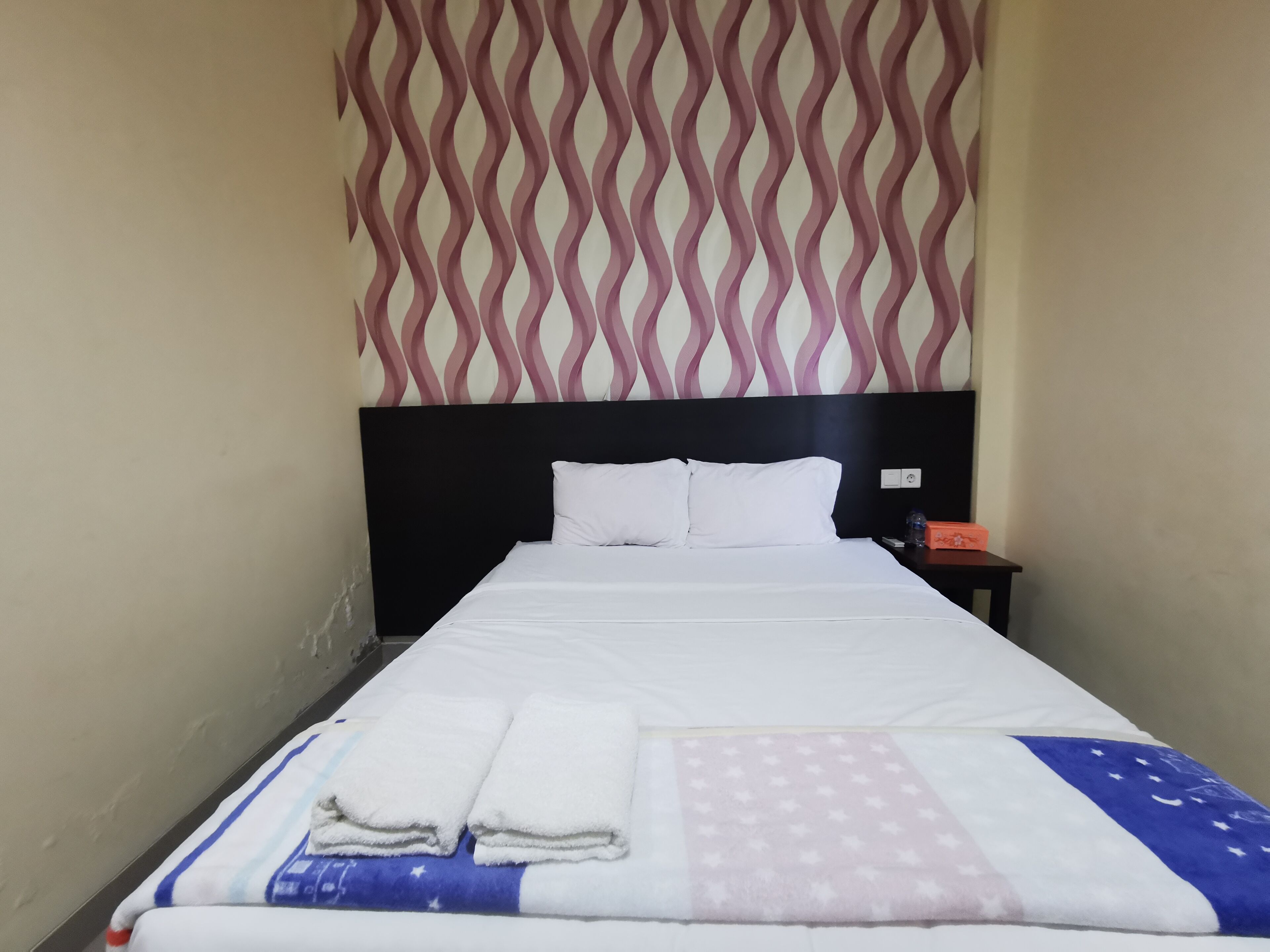 Cama bem arrumada com lençóis brancos e manta azul e branca.