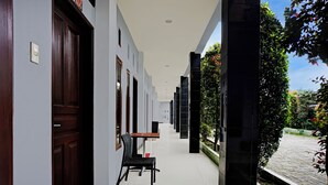 Um corredor com uma porta de madeira, uma cadeira e uma mesa.
