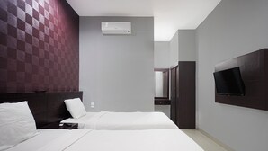 Quarto de hotel com duas camas, uma televisão de tela plana na parede e um aparelho de ar condicionado.