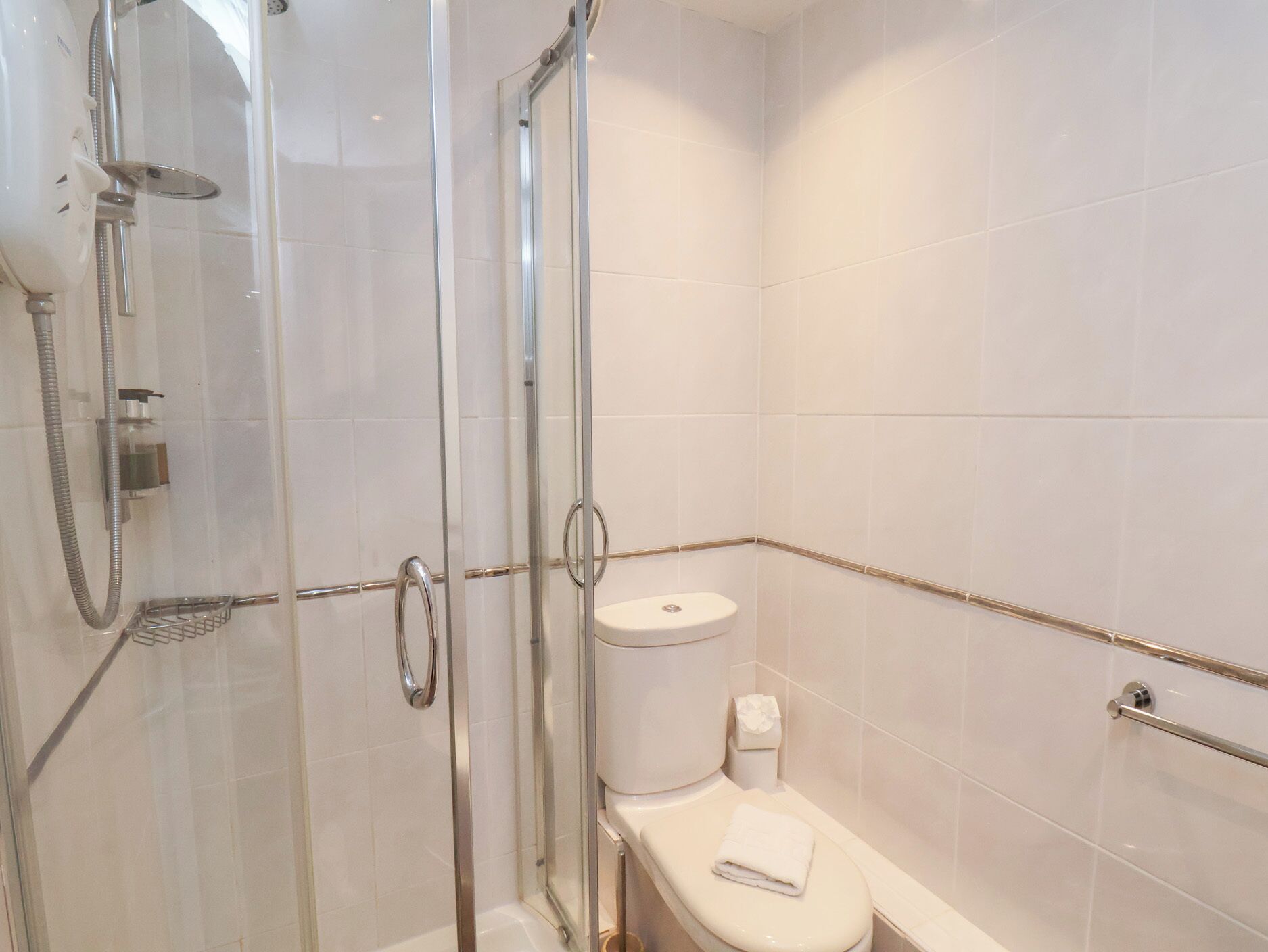 Uma casa de banho moderna com chuveiro em cabine de vidro, sanita e lavatório.