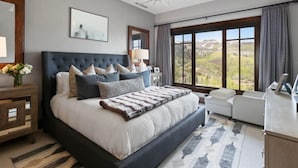 Quarto espaçoso com uma cama grande, vista para o exterior e um lustre moderno.